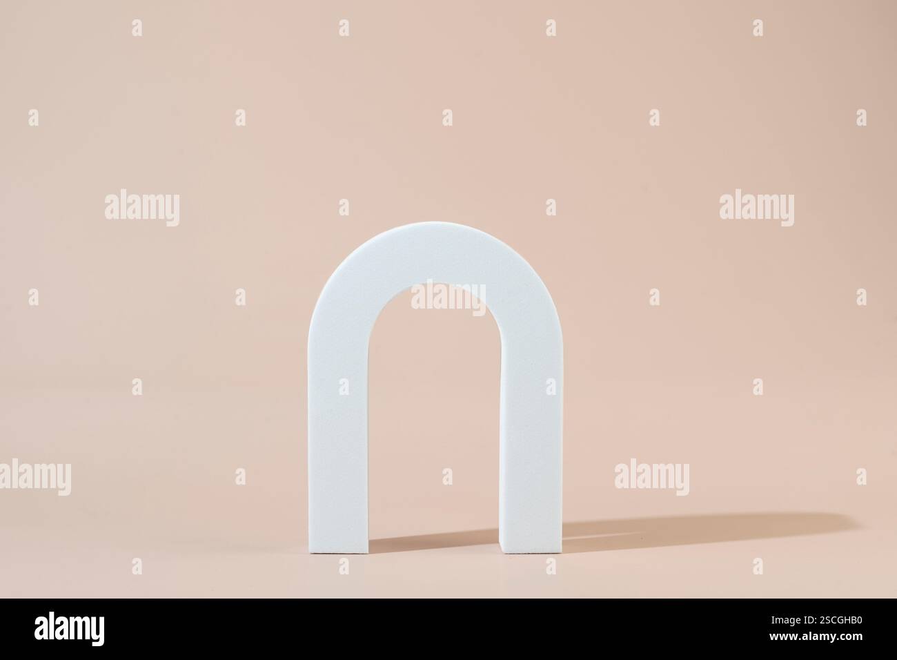 A white geometric shape in the form of the arch standing on a beige ...