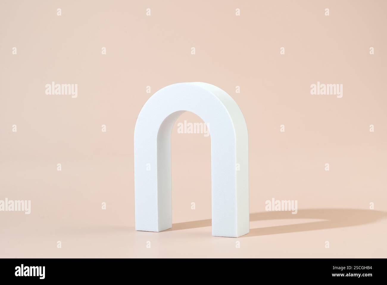 A white geometric shape in the form of the arch standing on a beige ...