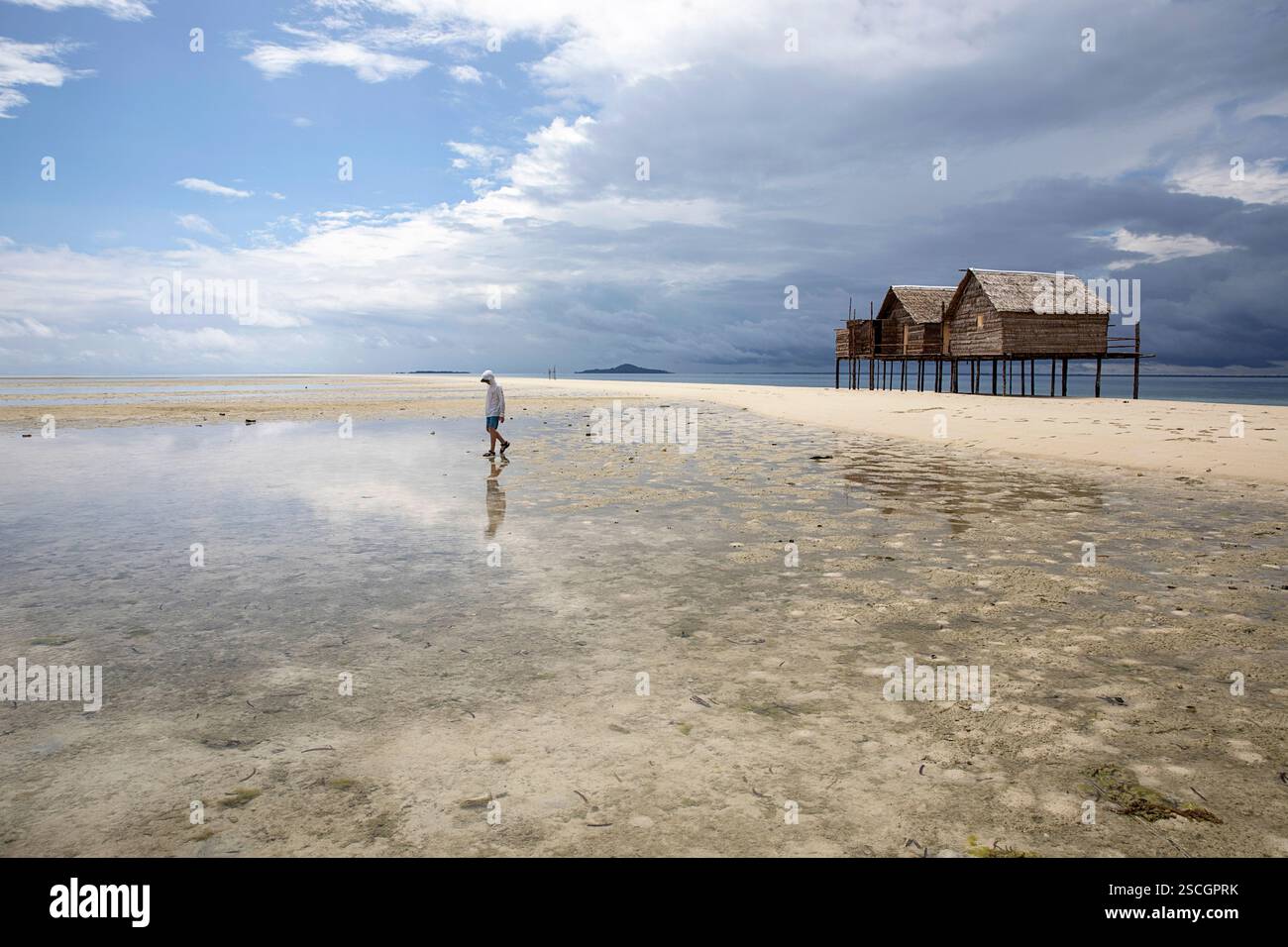 Tourist exploring remote sandbank with traditional bajau wooden houses ...