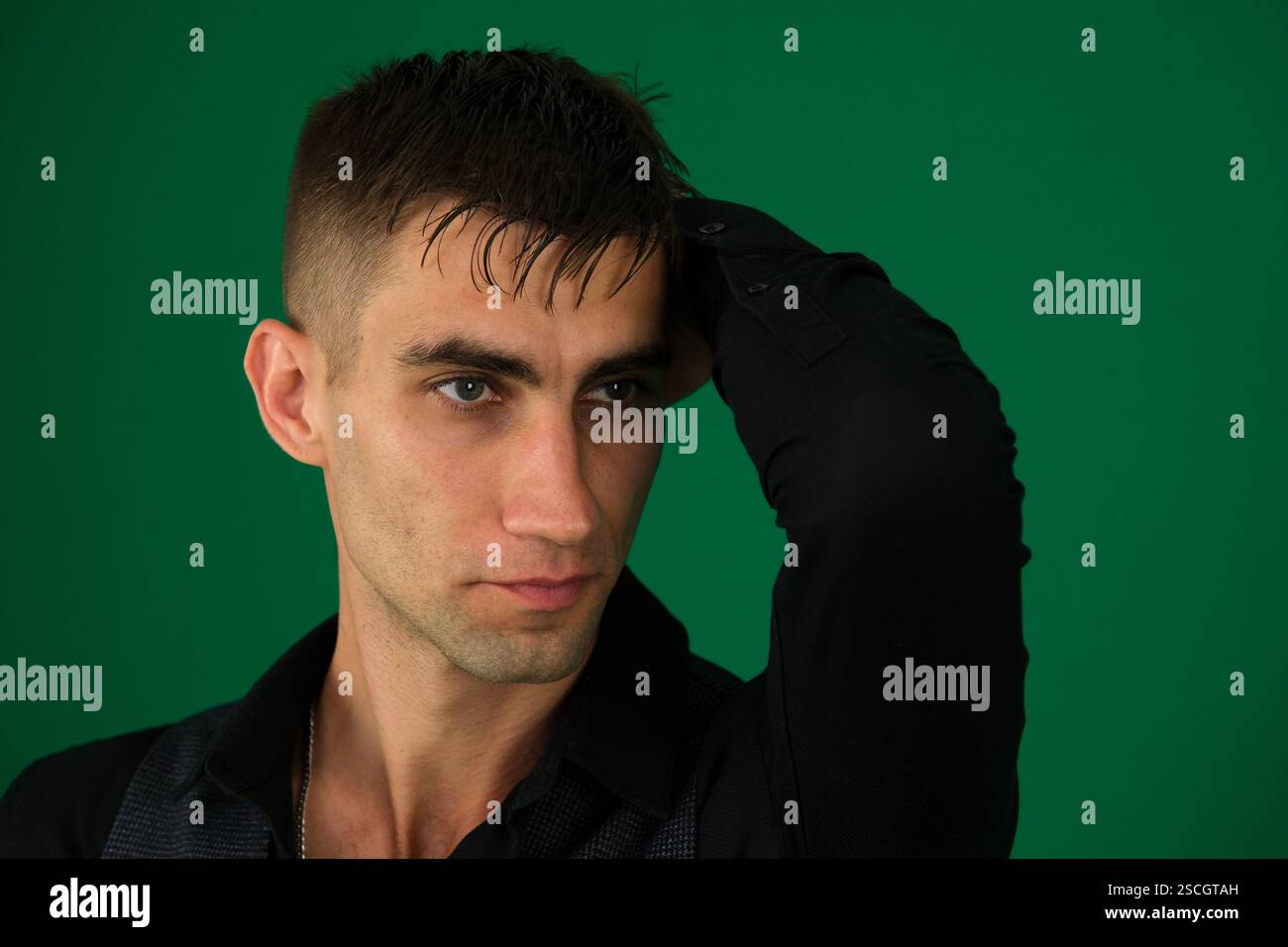 Young man in a green shirt with a concerned expression, holding his ...