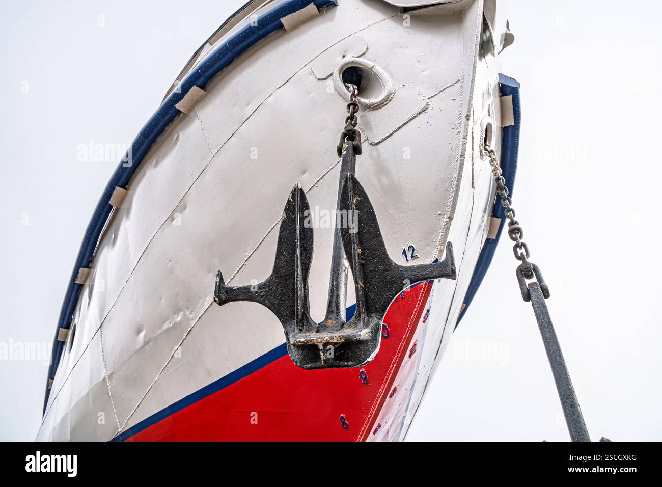 Ship's bow with a red and white hull, flanked by two large anchors on ...