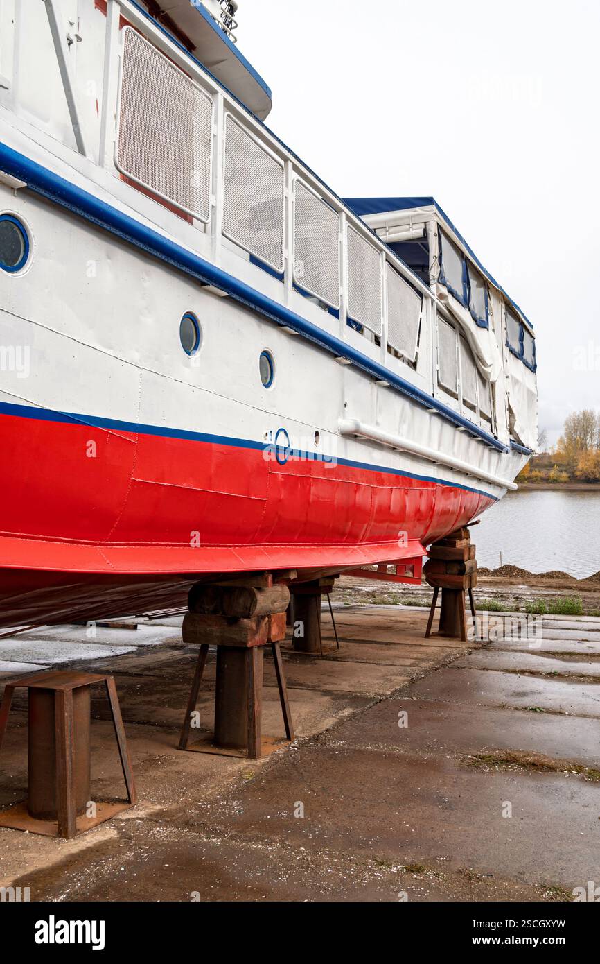 White and red ship raised on blocks for maintenance at dry dock near ...