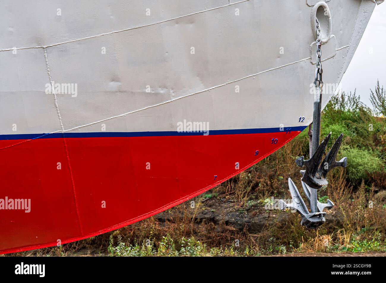 Ship's bow with a red and white hull, flanked by two large anchors on ...