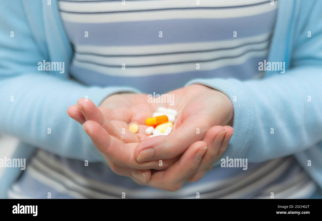 Hands cradle an assortment of pills in bright colors, showcasing a ...
