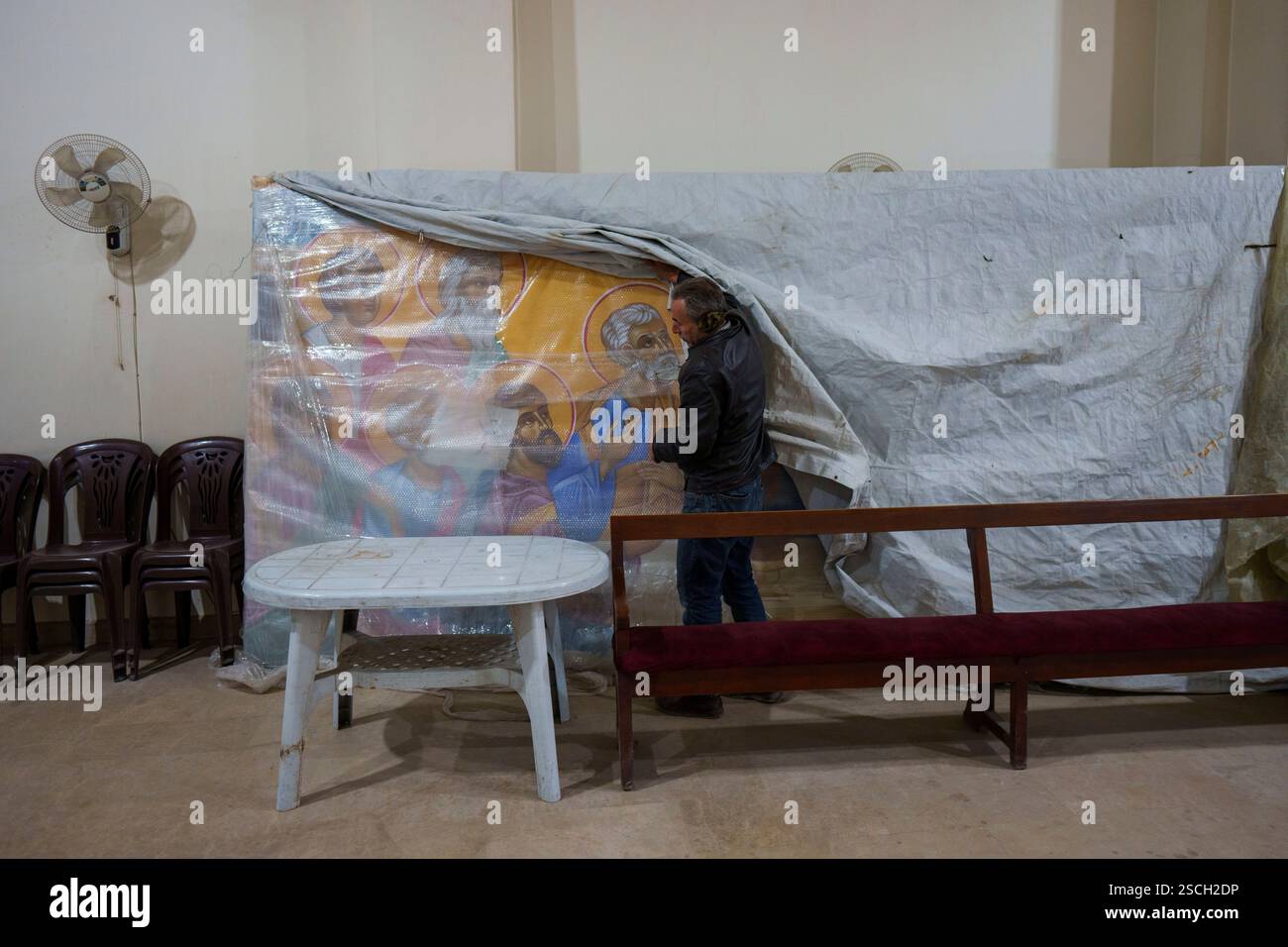 A worker unveils a religious painting inside the Syriac Orthodox Church ...