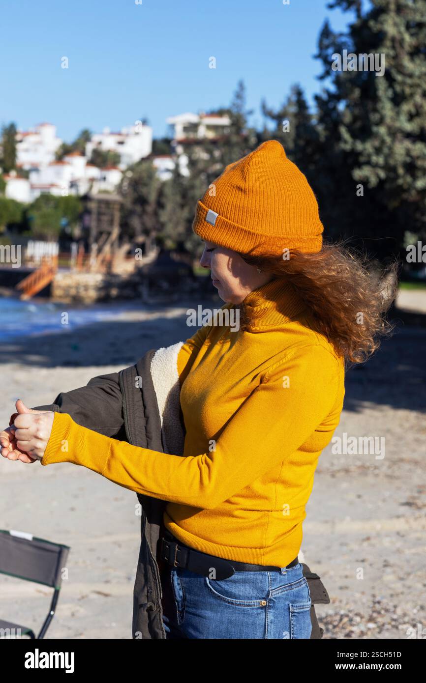 Cheerful young woman taking off jacket on a sunny windy day outdoors ...