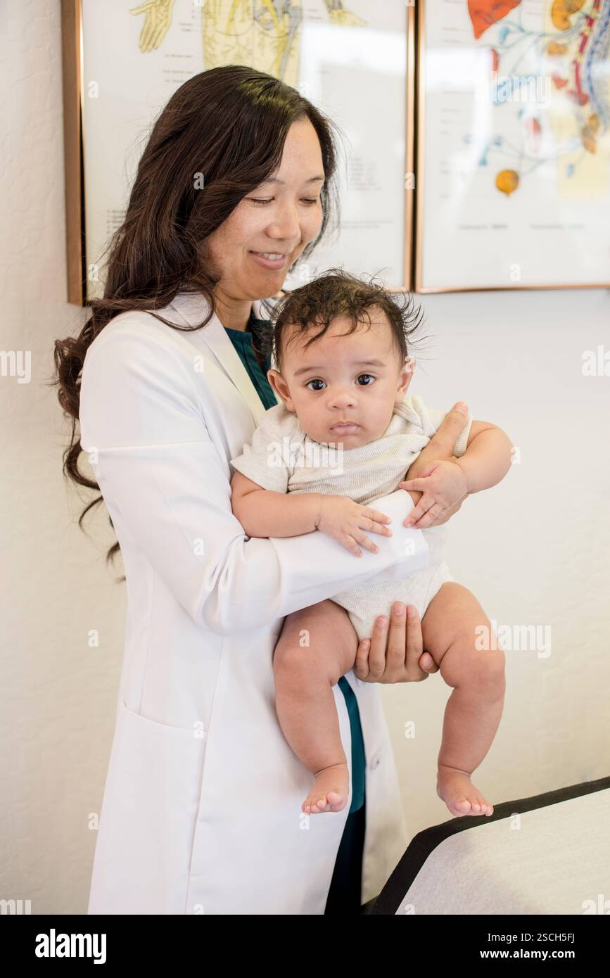 Doctor holding infant in doctors office Stock Photo - Alamy