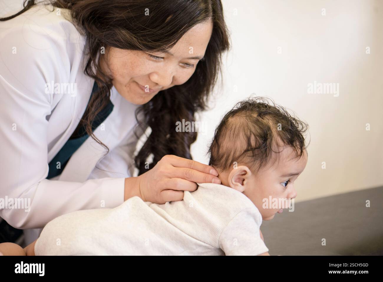 Doctor checking baby's neck in office Stock Photo - Alamy
