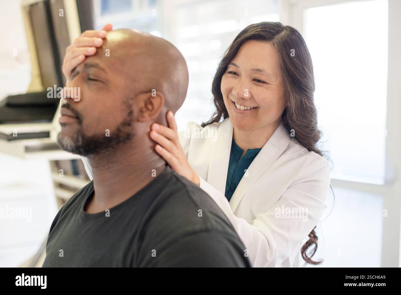 Doctor smiling while evaluating patients neck Stock Photo - Alamy