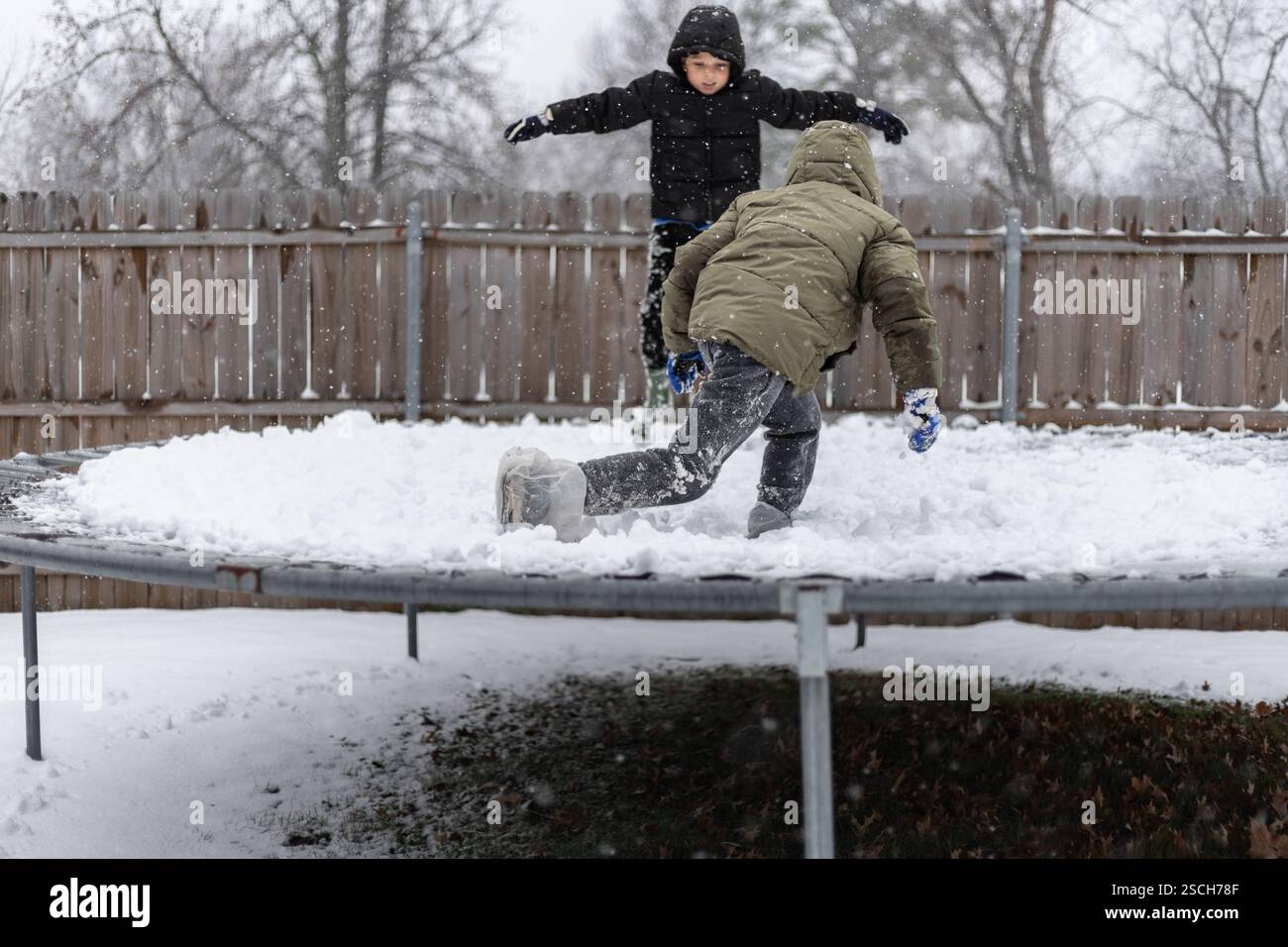 Kids playing on a snowy trampoline in a winter backyard scene Stock ...