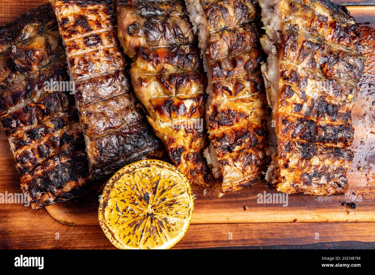 Deliciously grilled fish fillets are sliced and presented on a wooden ...