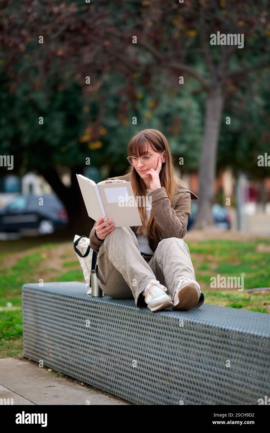 Woman reading a book with concentration on a bench in a park Stock ...