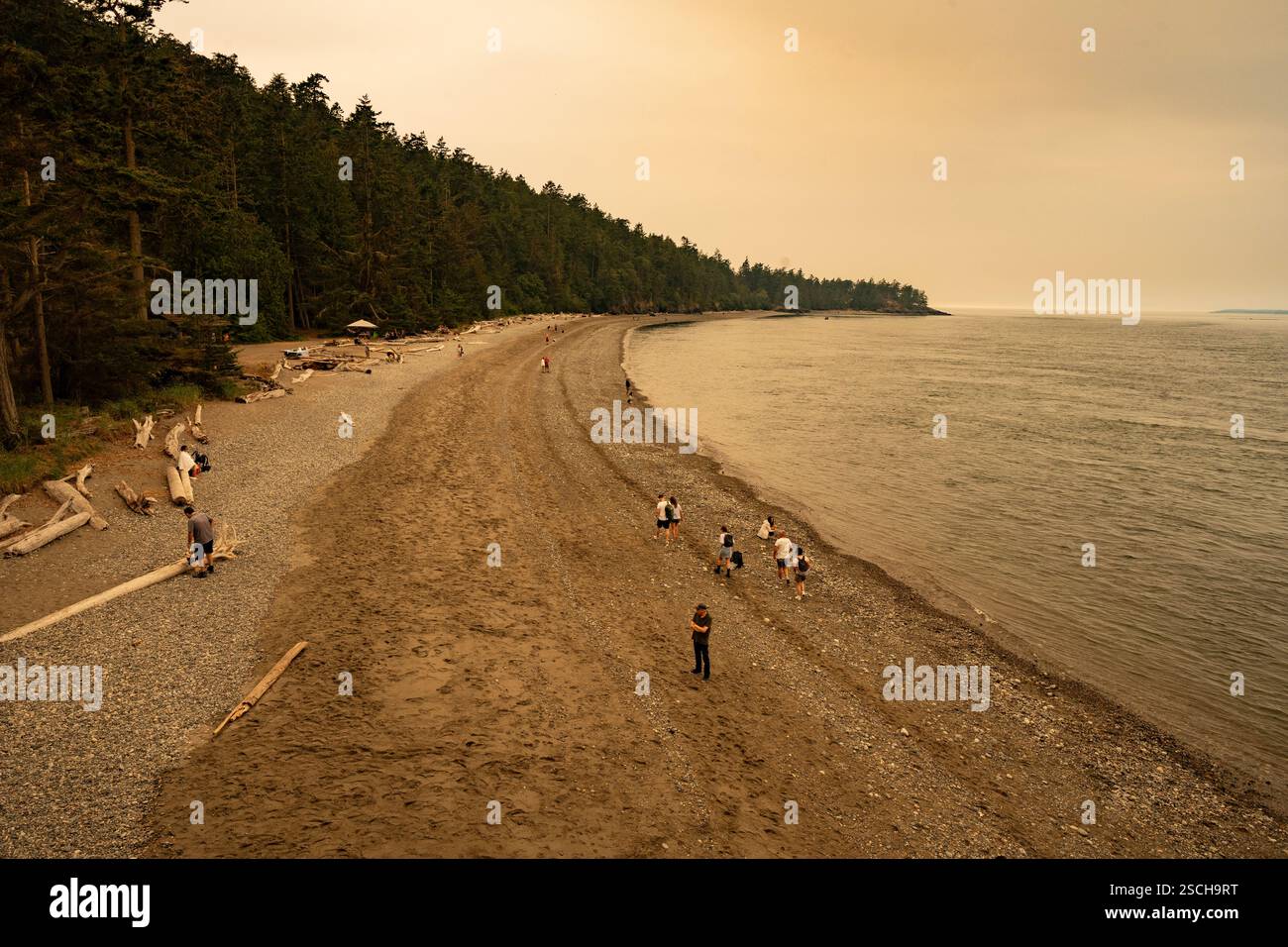 People explore the beach while smoke fills the air, Deception Pass ...
