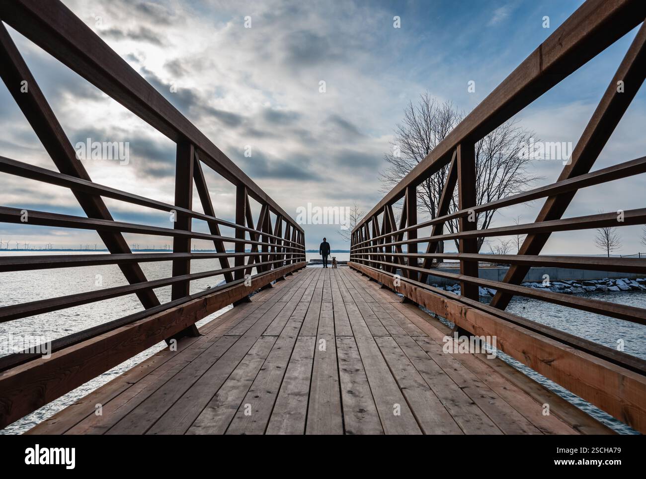 Low angle of man walking dog across bridge on winter day Stock Photo ...