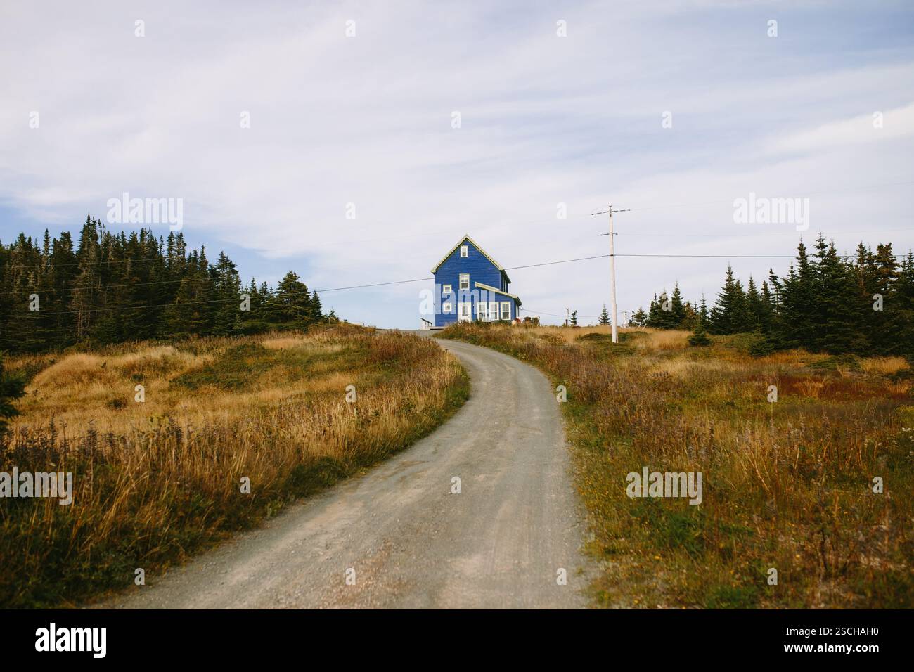 A striking blue house stands isolated along a winding dirt road ...