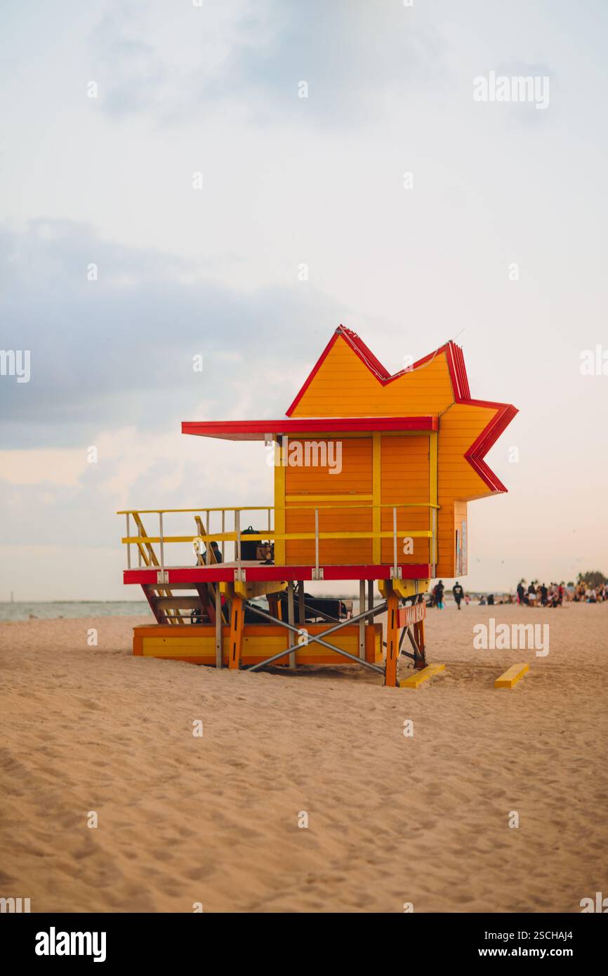 A bright red and yellow lifeguard tower stands vibrantly against a soft ...