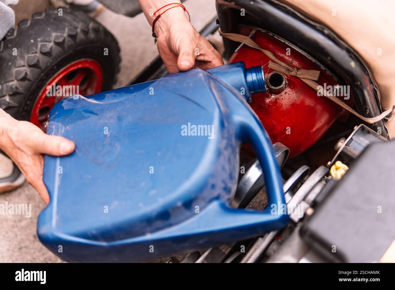 Cropped image of unrecognizable person pouring fuel from a blue ...