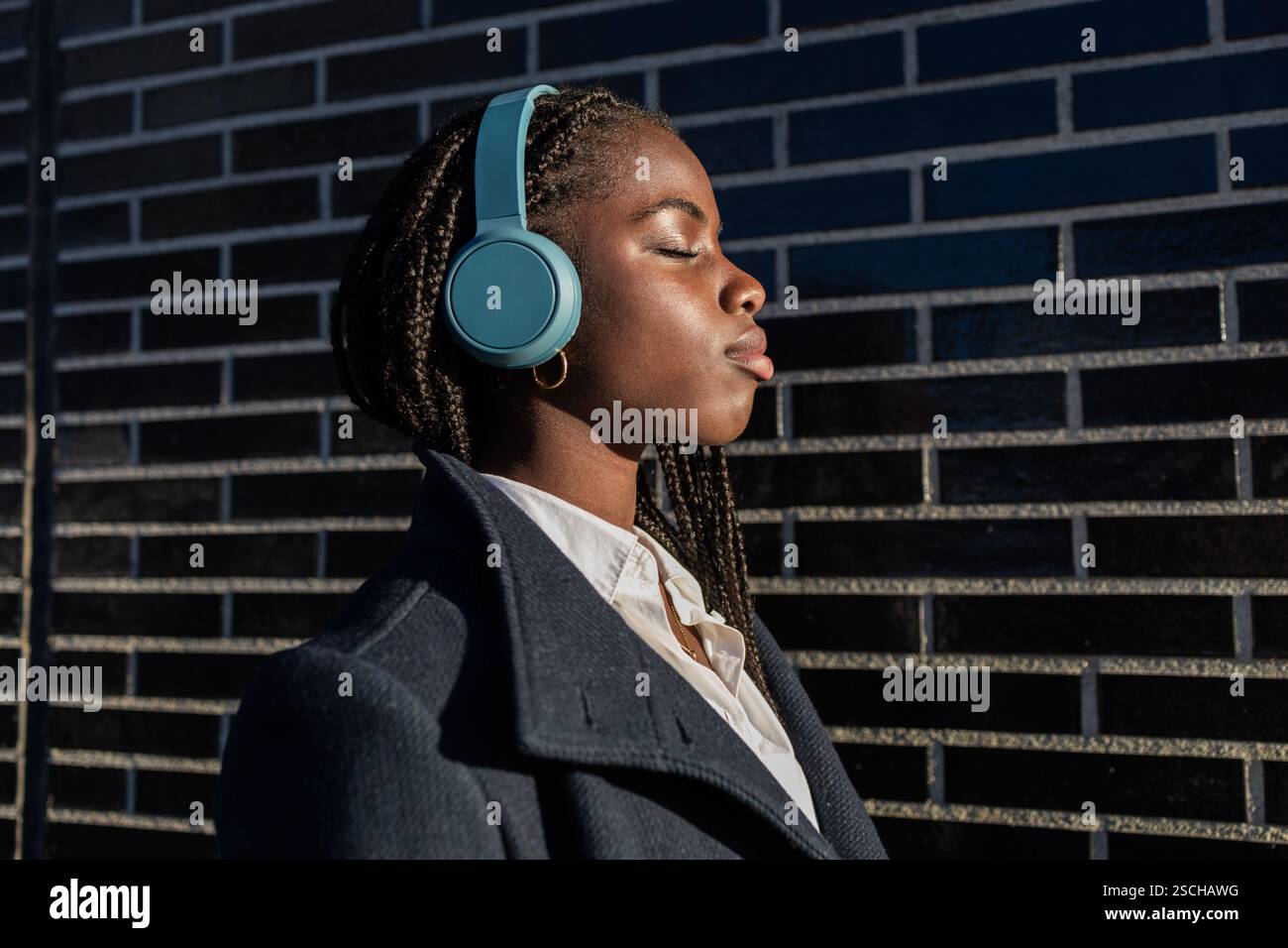 An African American businesswoman with braids enjoys a break, listening ...