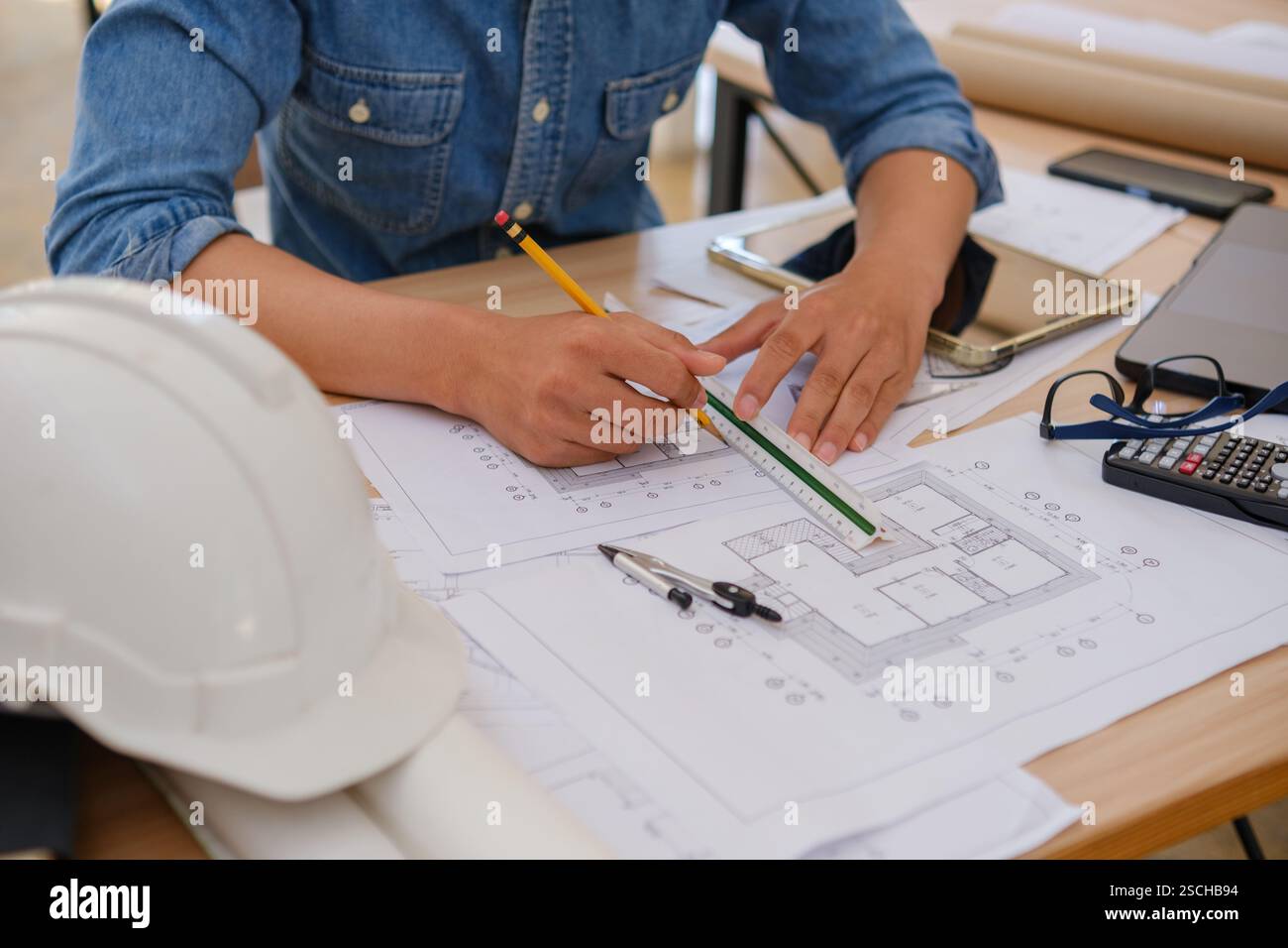Architect working on blueprints at a modern workspace Stock Photo - Alamy