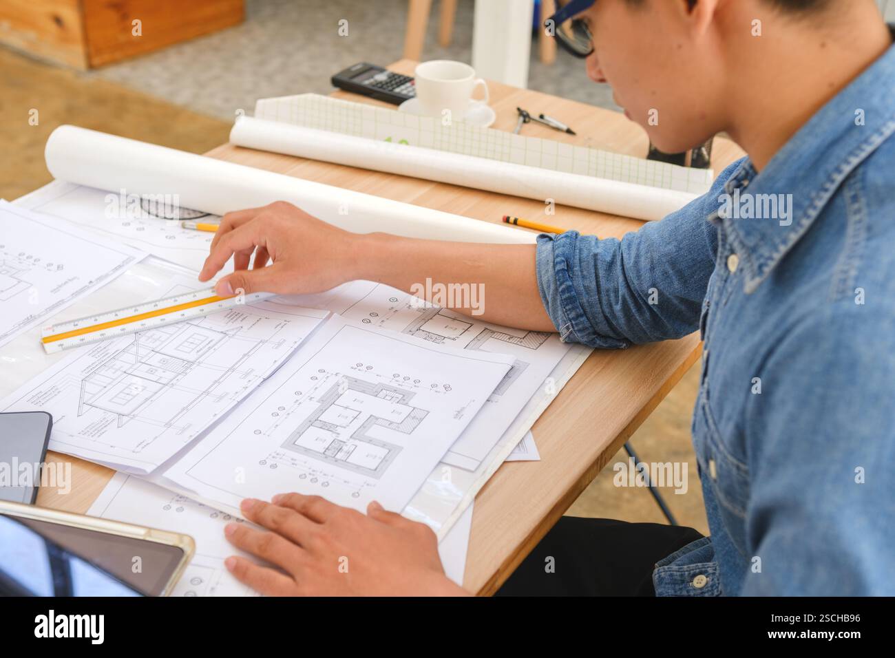 Architect working on blueprints at a modern workspace Stock Photo - Alamy