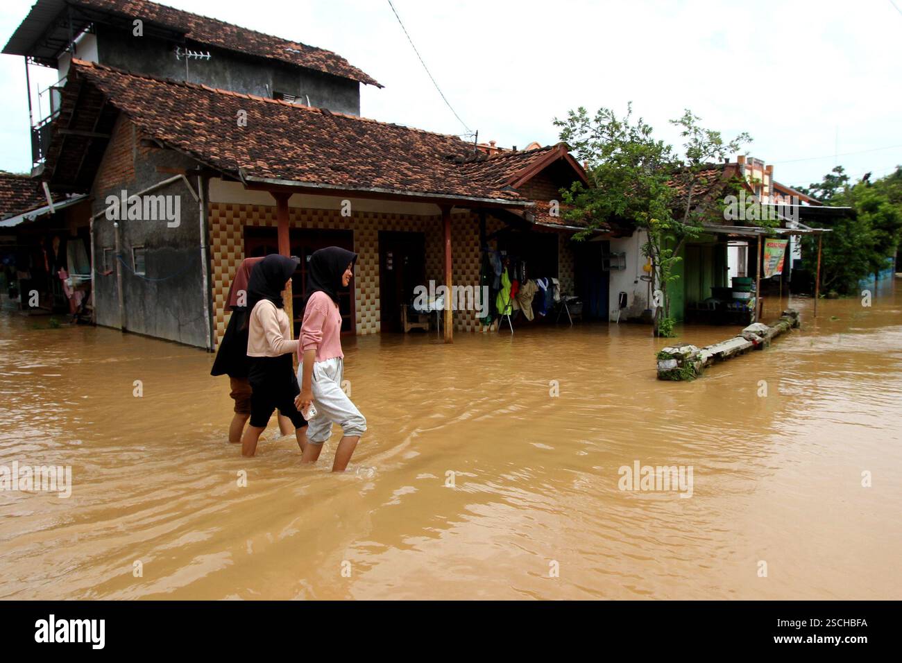 Kudus, Indonesia. 7th Feb, 2025. People walk through flood water after ...