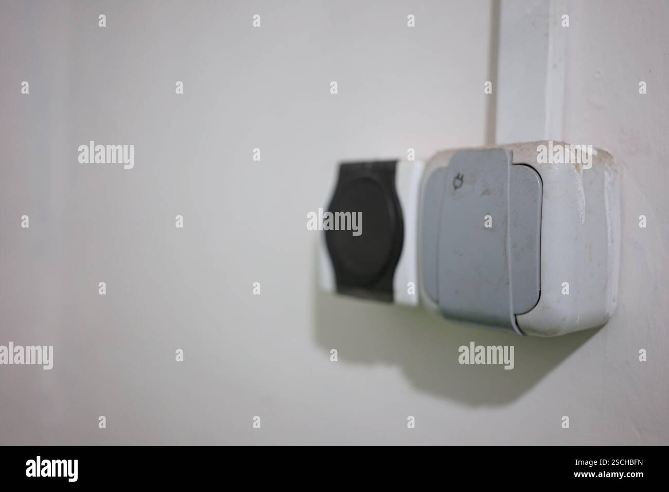 Two electrical outlets are mounted on the wall, one is showing wear ...