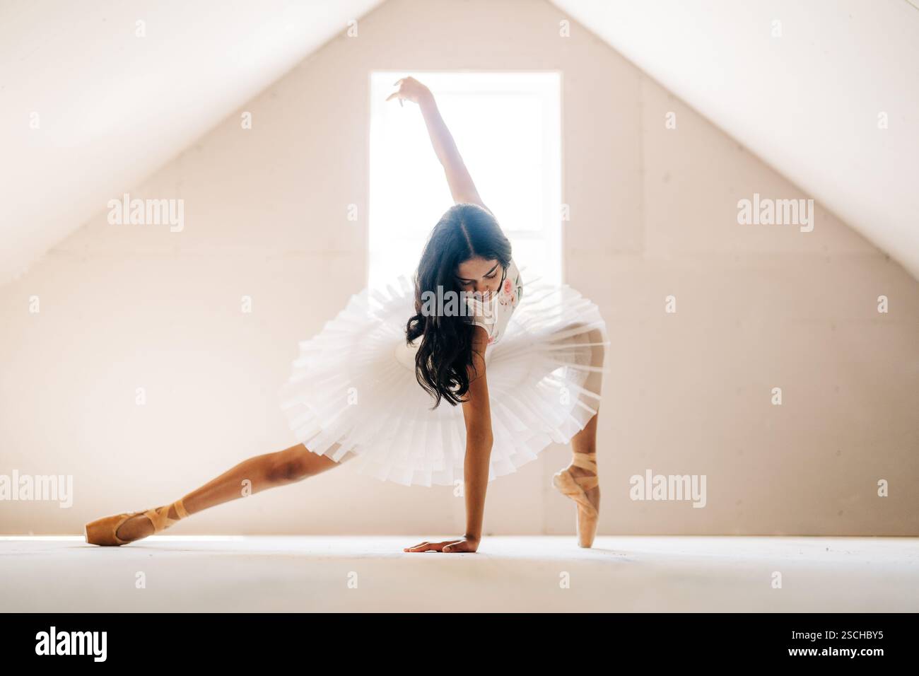 Ballerina in a white tutu performing a dynamic pose in a loft Stock ...