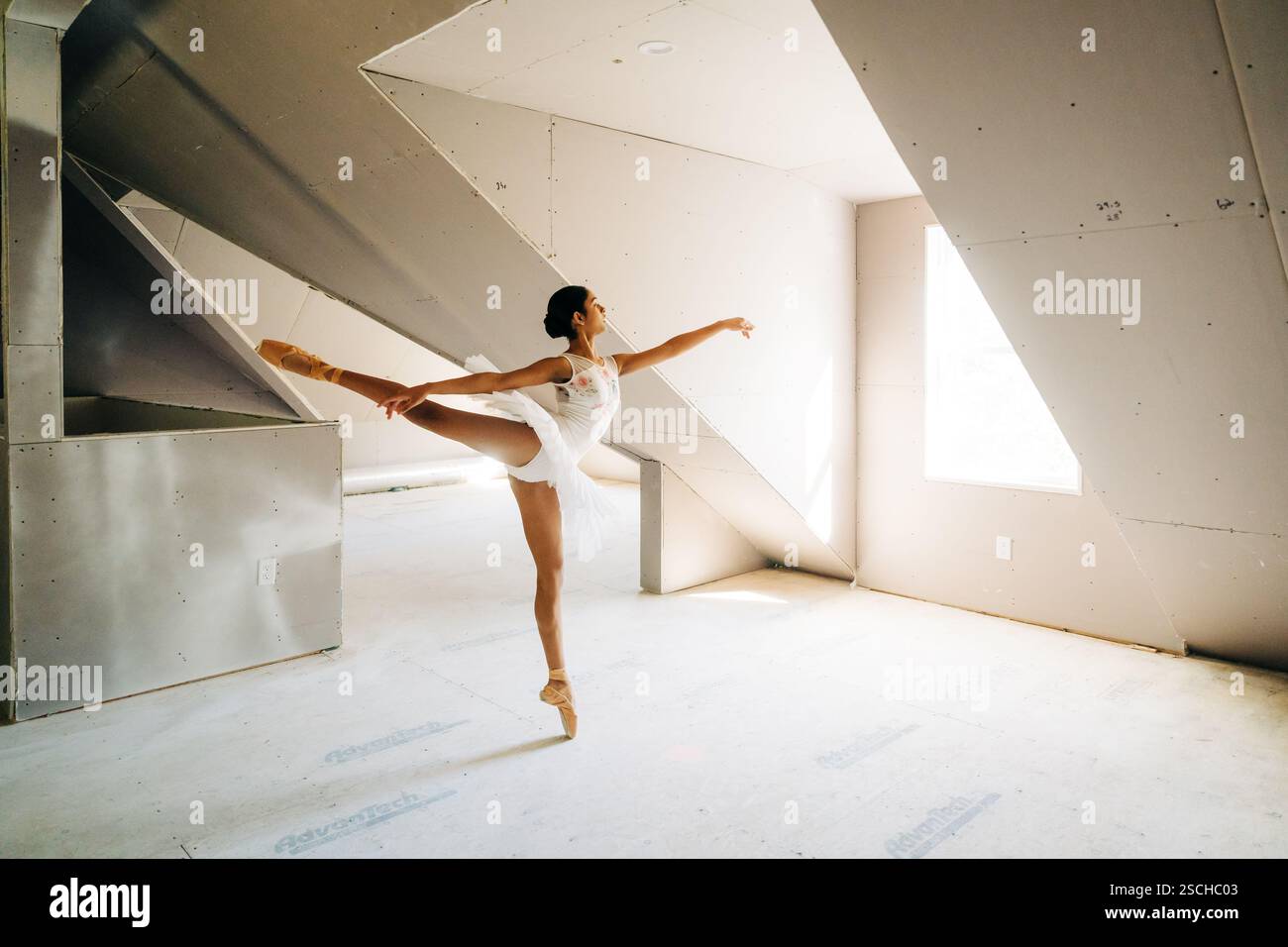 Ballerina en pointe in an arabesque pose, gracefully lit in a loft ...