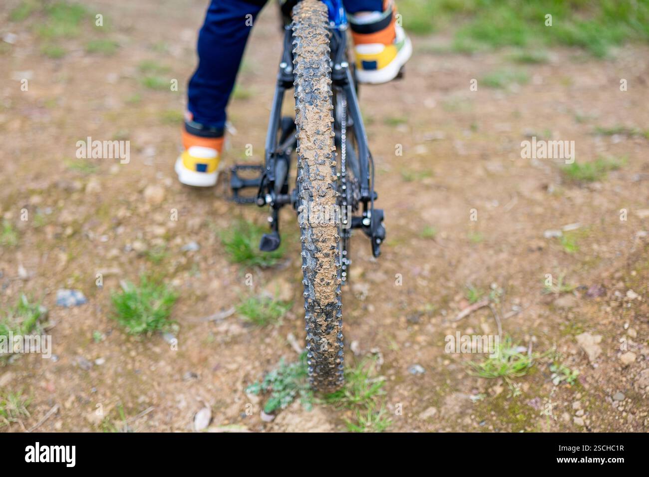 A close up of a muddy bicycle tire capturing a child journey along a ...