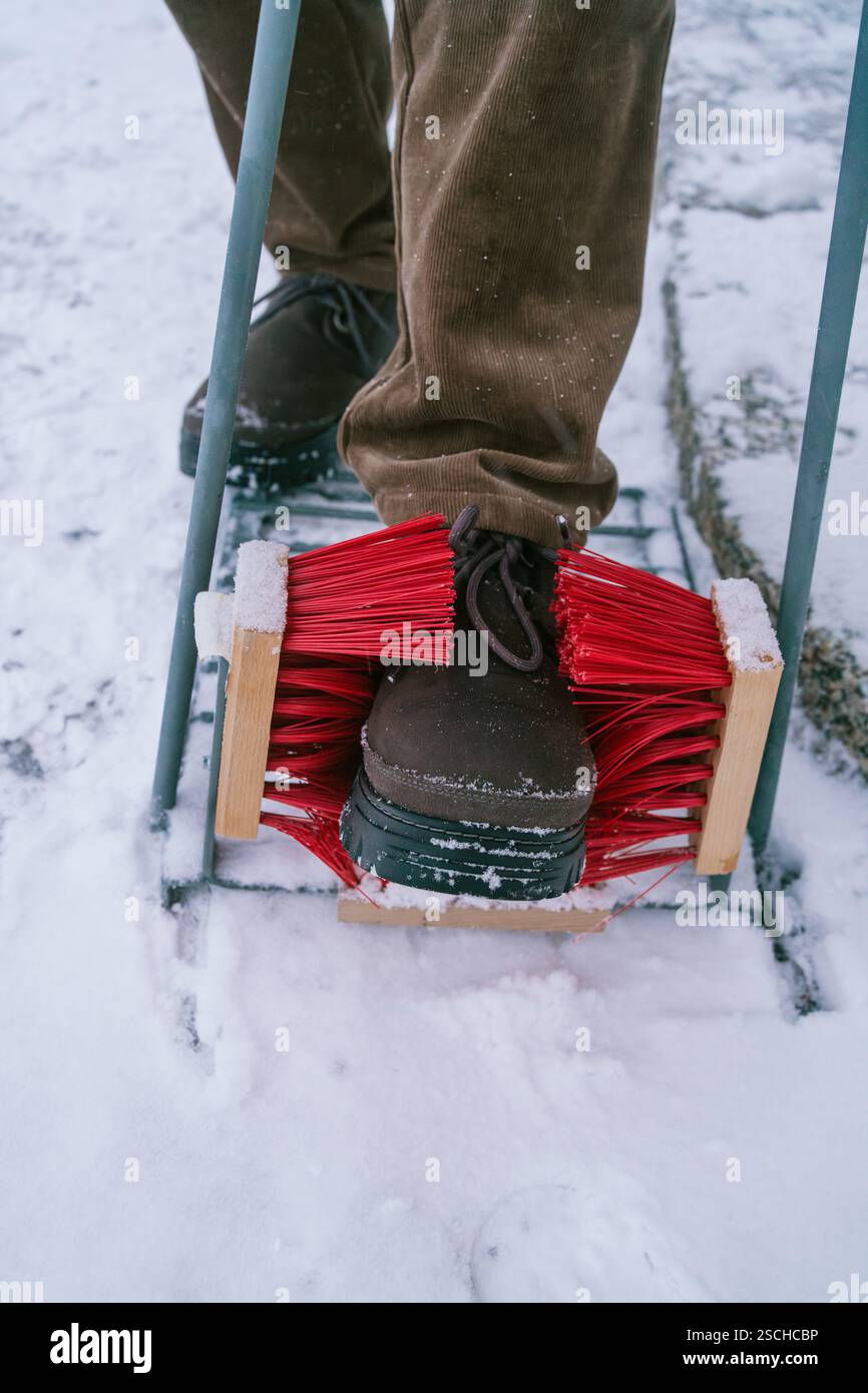 A close-up of a boot being brushed by a red-bristled cleaning device in ...