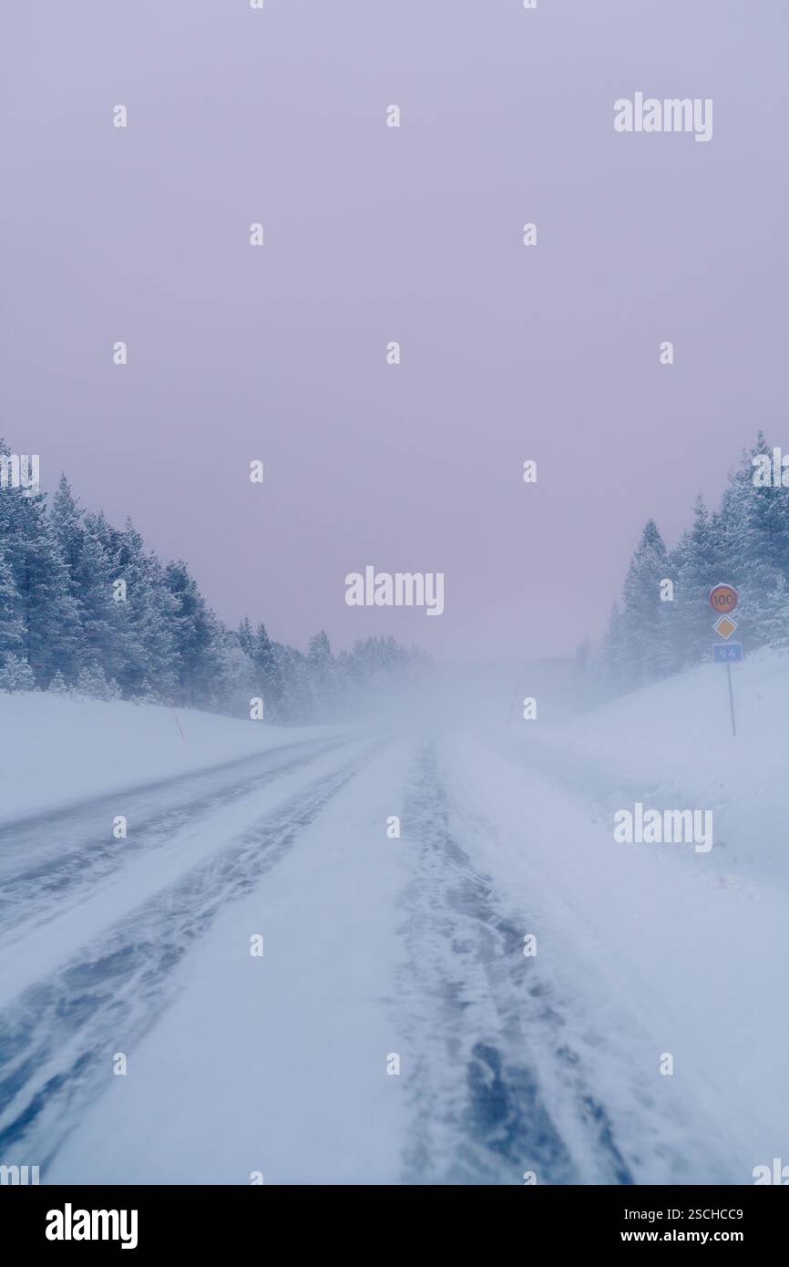 An icy road stretches through Swedish Lapland, flanked by frost-covered ...