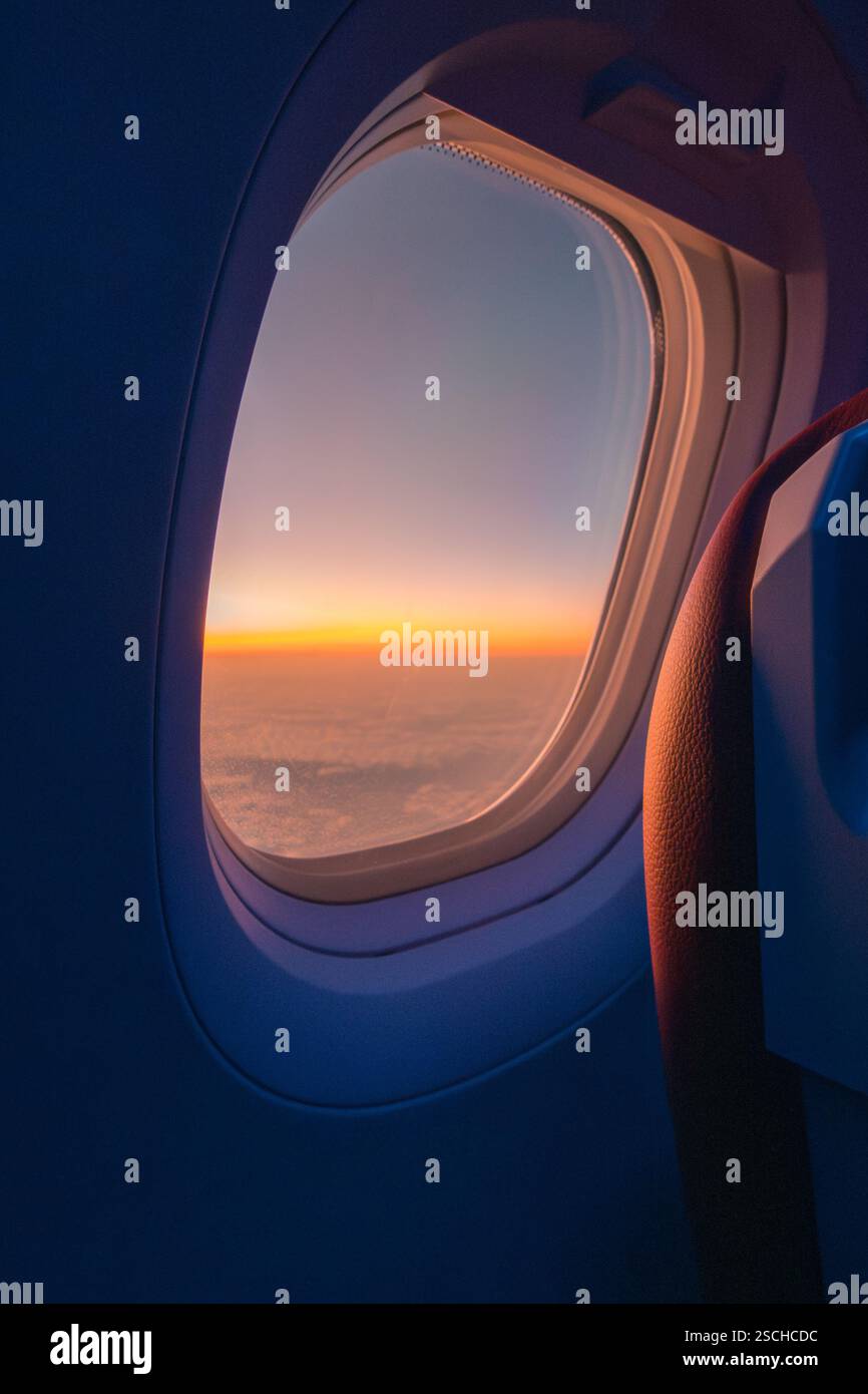 A serene sunset visible through the oval window of an airplane ...