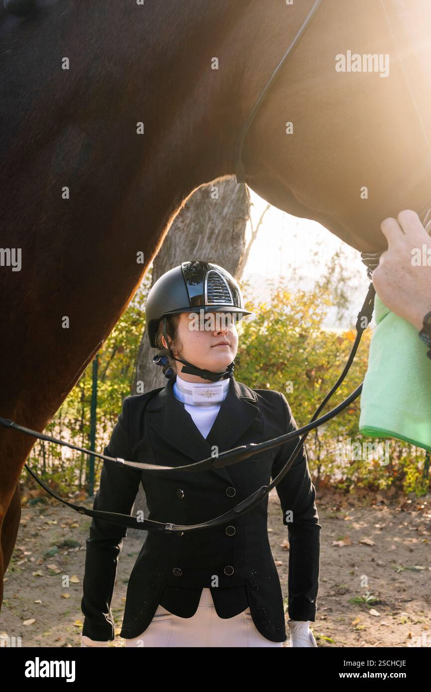 A young dressage rider in formal attire stands with their horse during ...