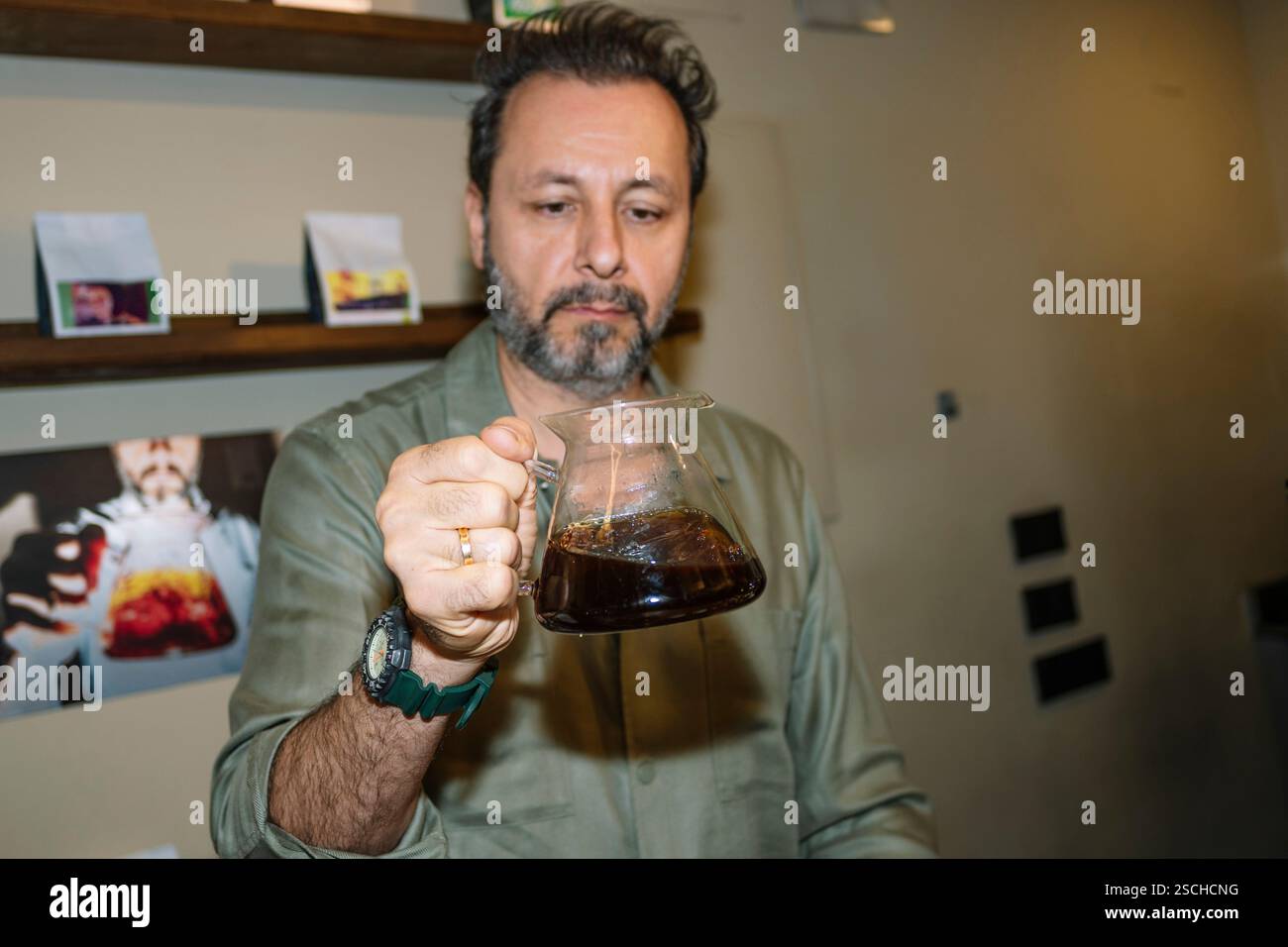 A coffee expert intently examines a glass carafe filled with specialty ...