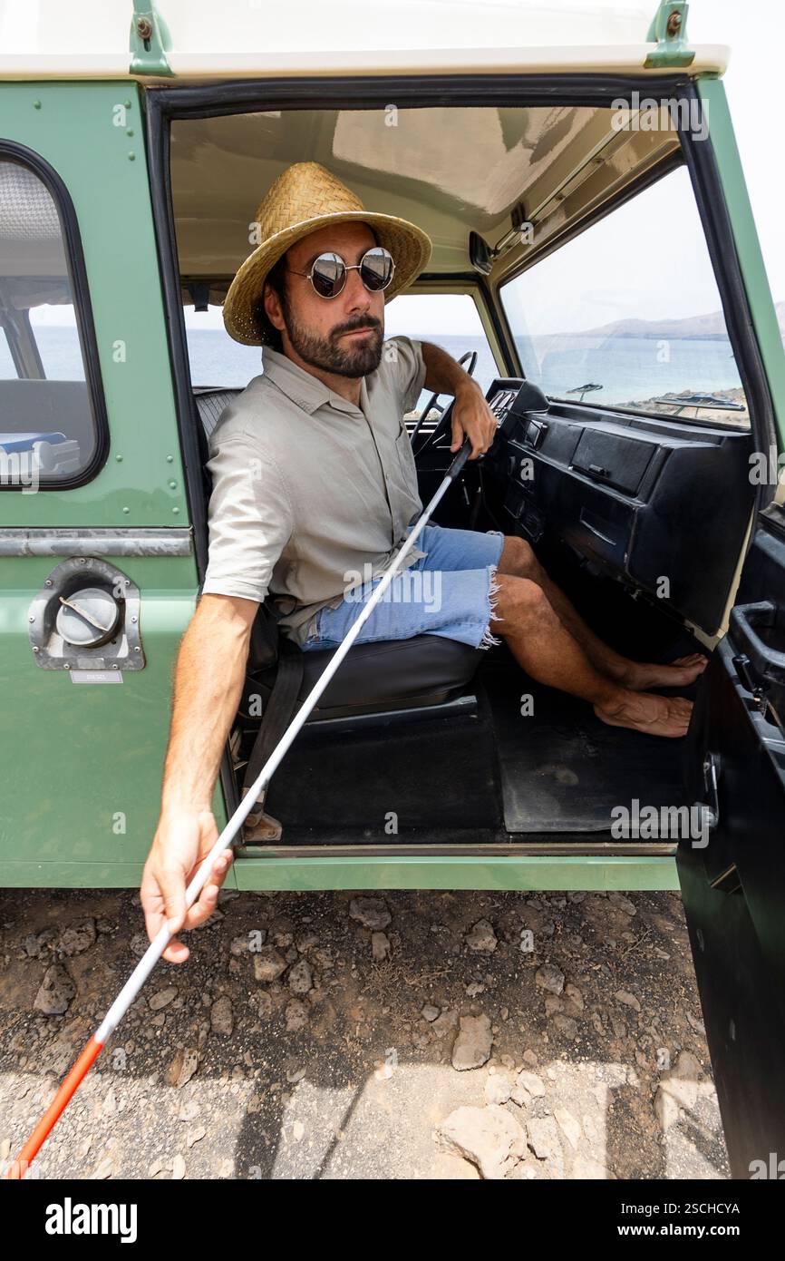 Blind man sitting in a motorhome, wearing sunglasses and a straw hat ...