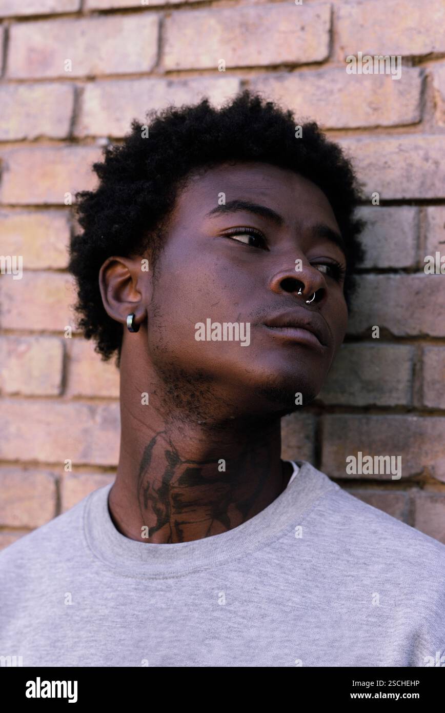 Portrait of a young black man gazing upward, standing confidently ...
