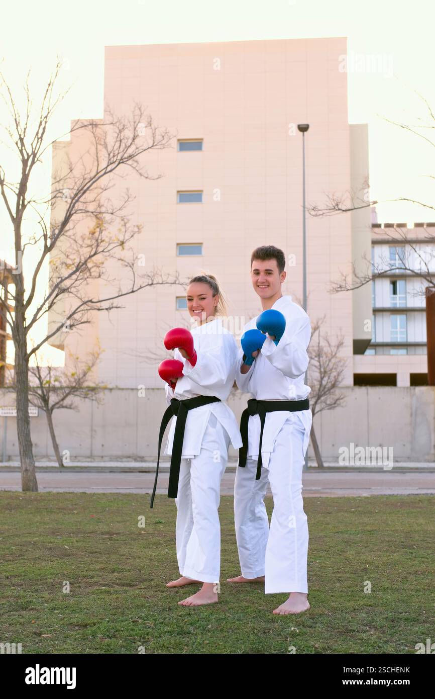 A young man and woman, both wearing karate gear with red and blue ...