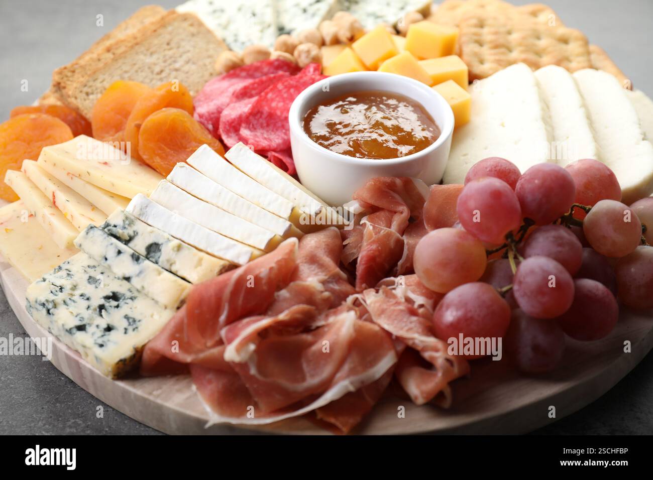 Different types of cut cheese and other snacks on grey textured table ...