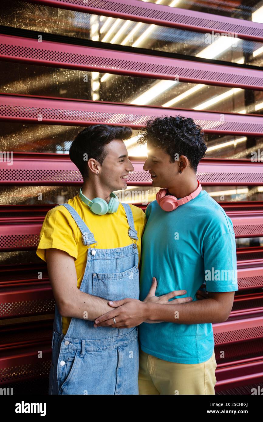 A joyful couple, wearing colorful casual outfits, share a loving moment ...