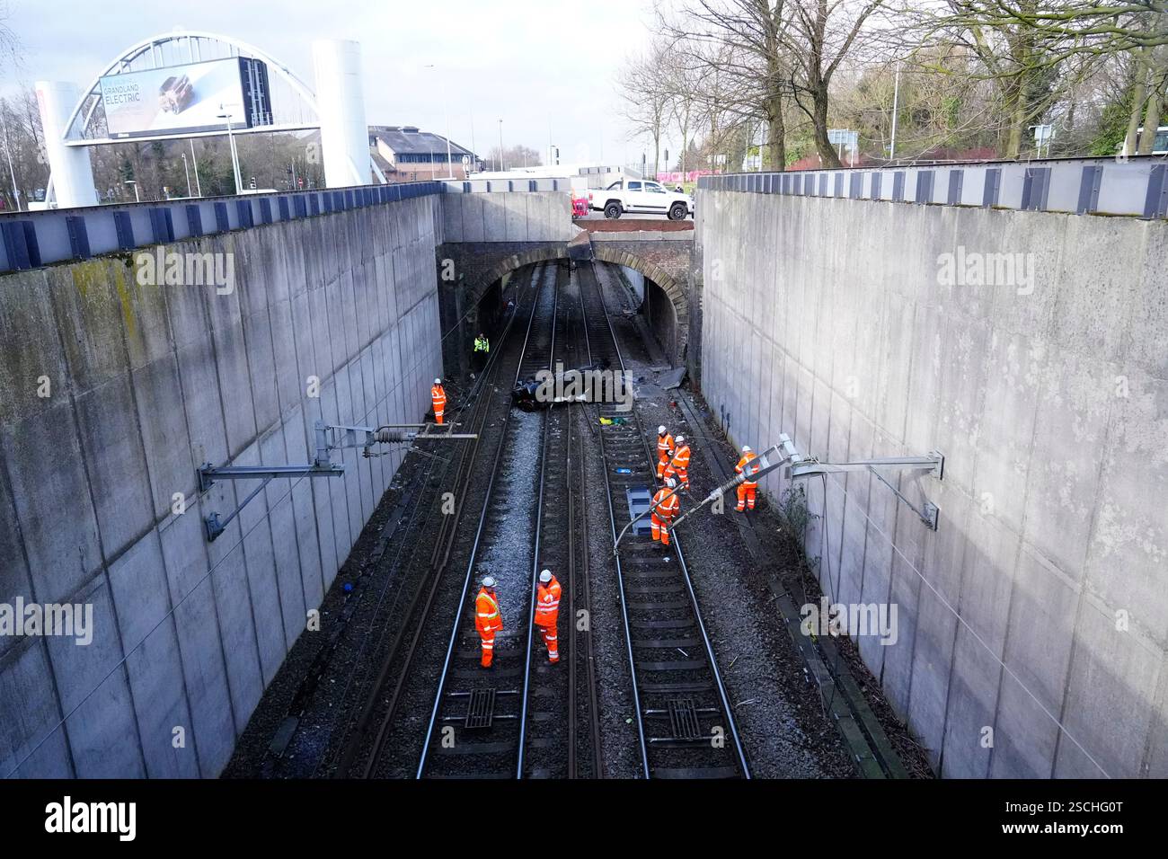 Emergency workers view a car that crashed onto tracks in Salford ...