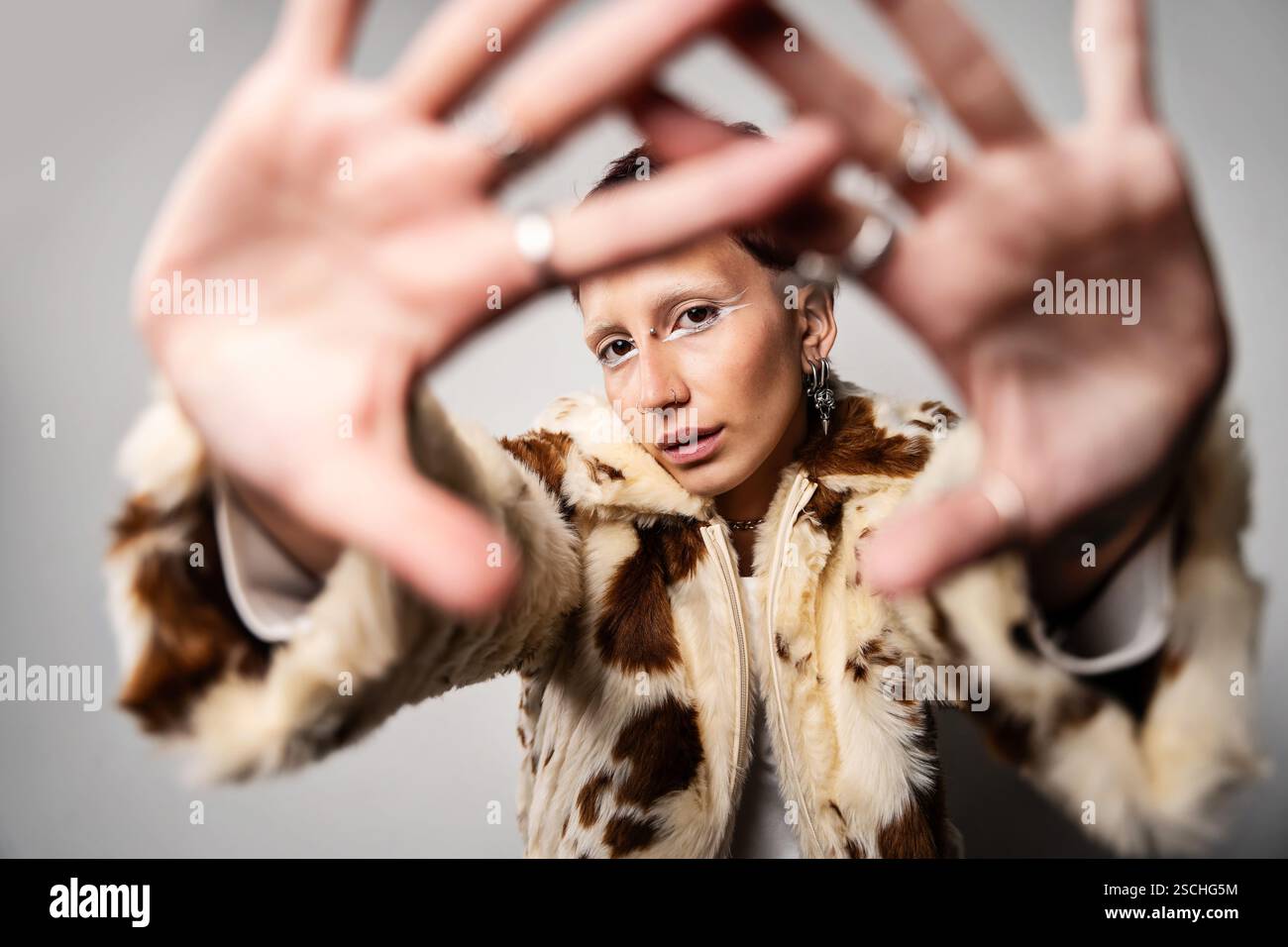 A woman wearing a stylish fur coat poses with hands stretched toward ...