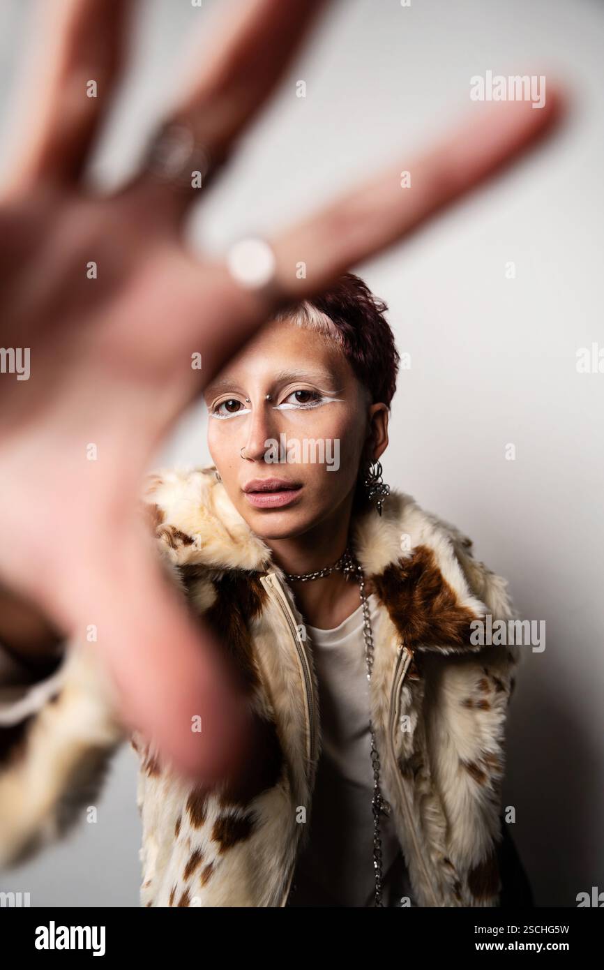 A woman wearing a stylish fur coat poses with hands stretched toward ...