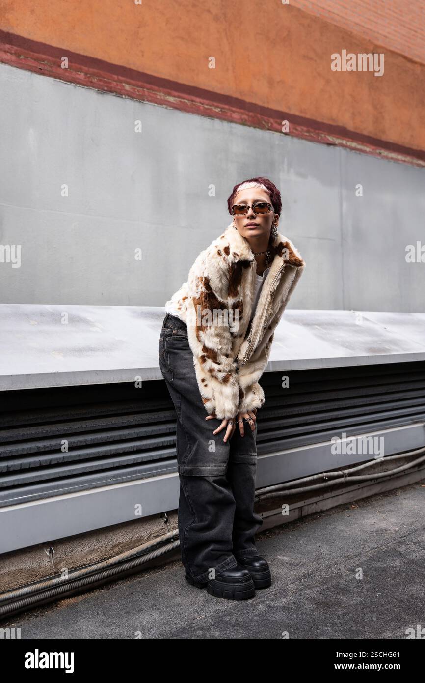 Stylish woman poses against an urban backdrop, showcasing a faux fur ...