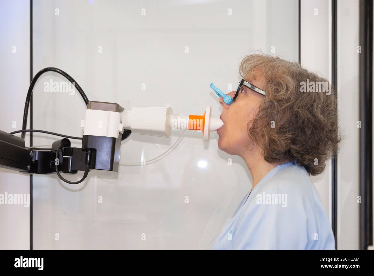 A woman is shown with nose clip performing a spirometry test to assess ...