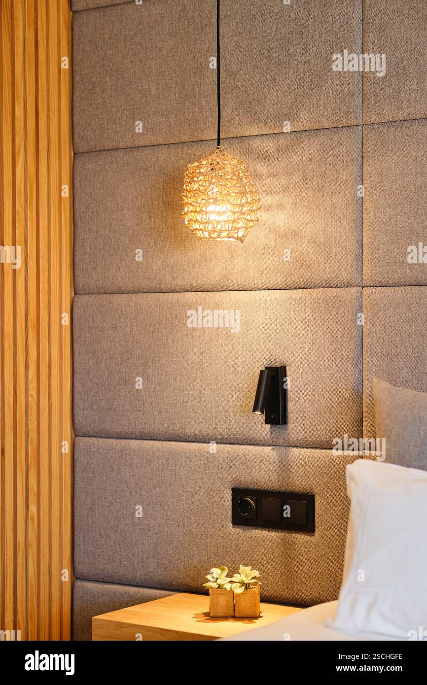 A serene hotel room with soft, woven pendant lighting, padded walls ...