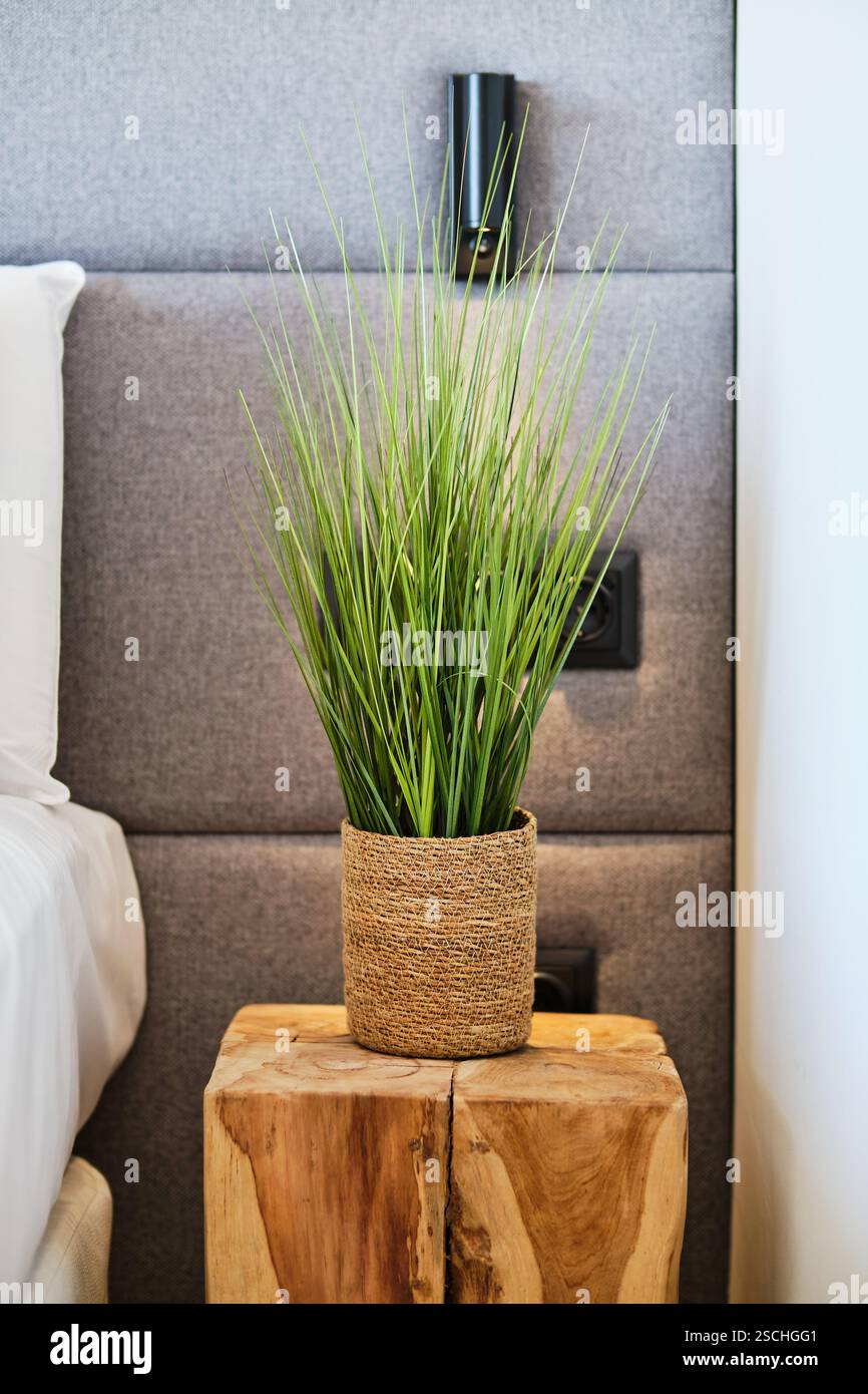 A modern hotel room detail featuring a wooden bedside table with a ...