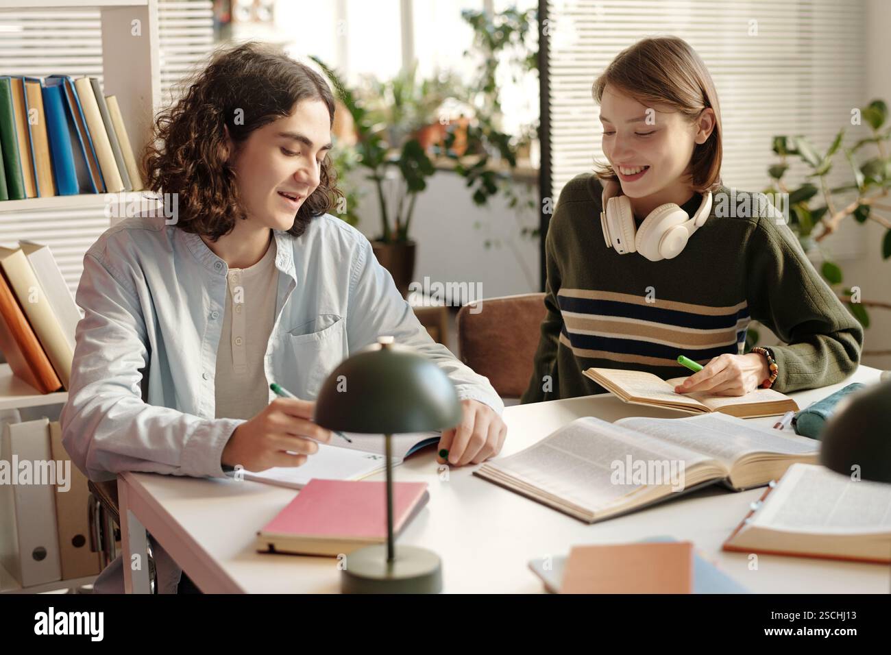 Two Smiling Students Studying at Desk in College Class Reading Textbooks Stock Photo - Alamy