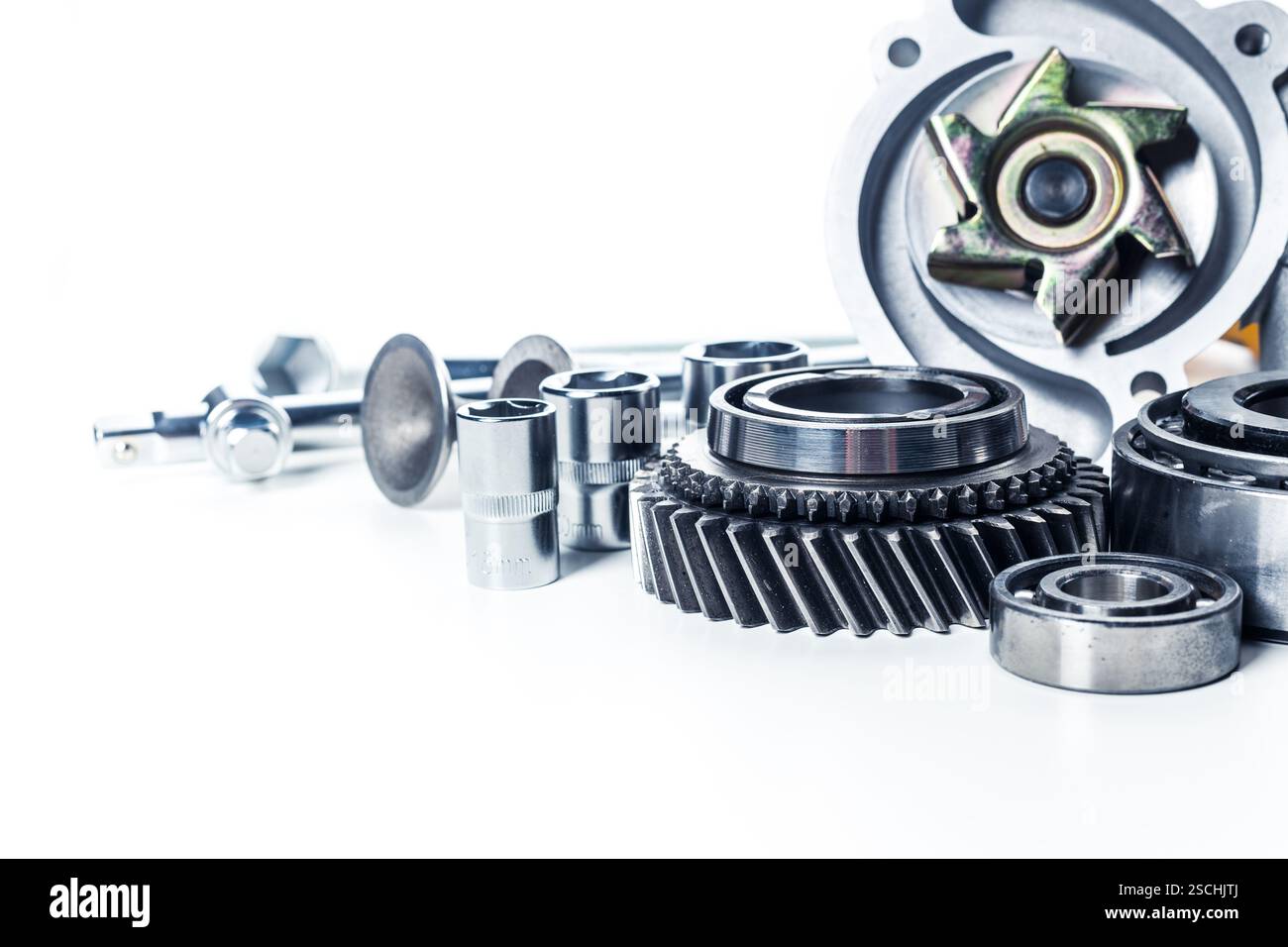 Collection of mechanical parts and tools arranged on a white surface ...