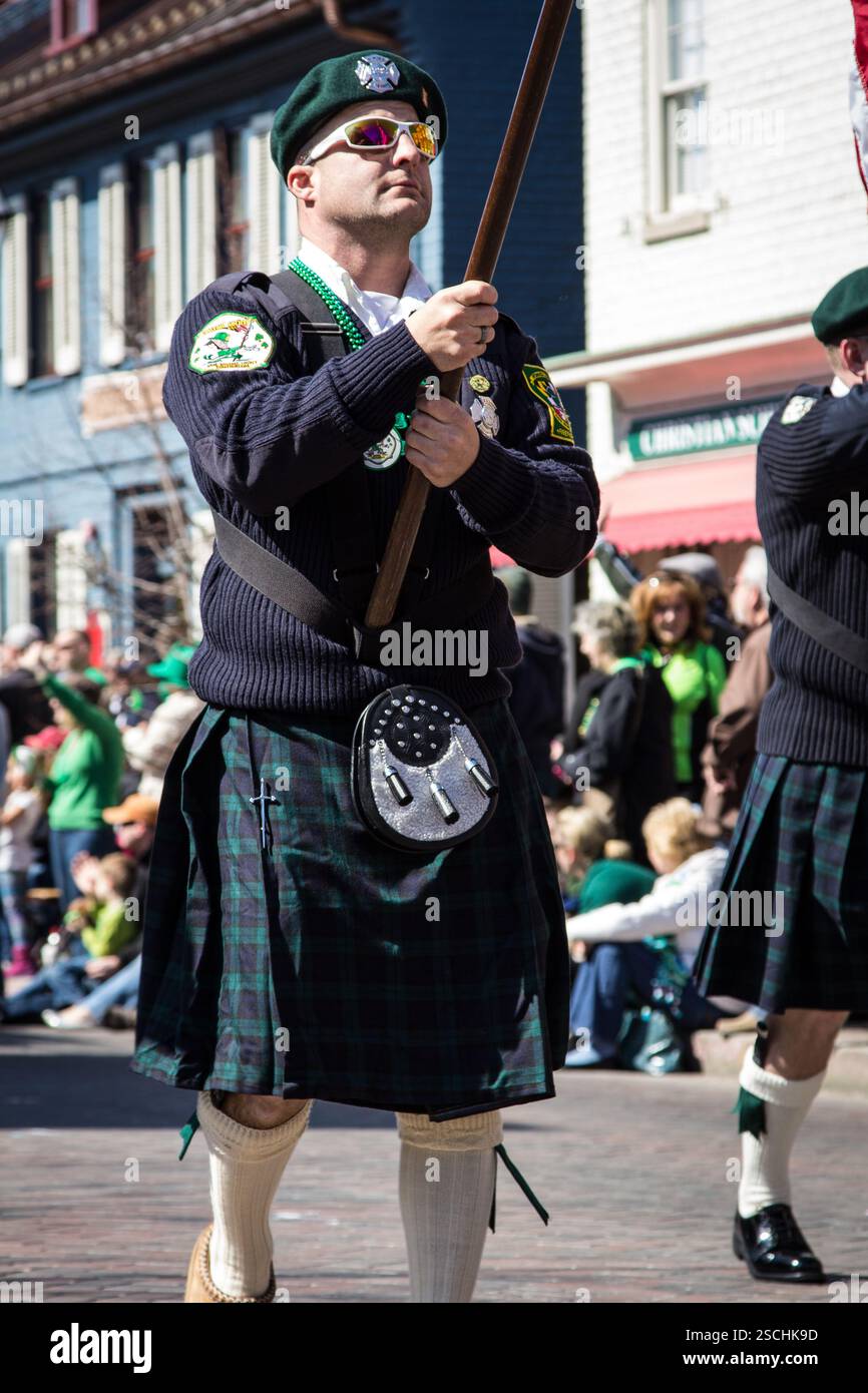 St. Patrick's Day parade. Men in kilts, carrying a flagpole, march ...