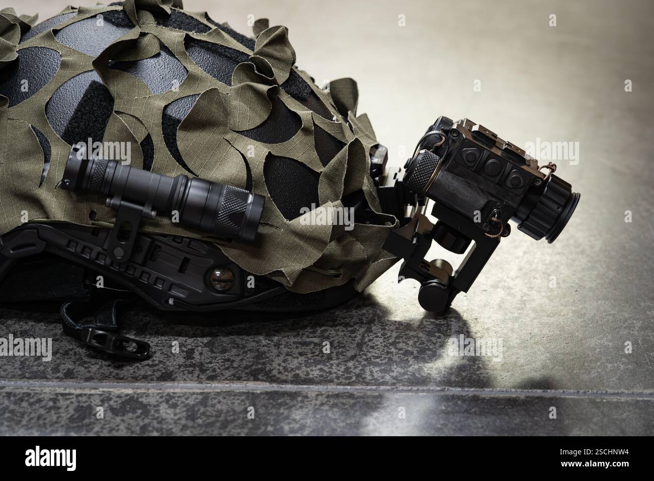 A tactical helmet with a thermal imaging monocular and a flashlight ...